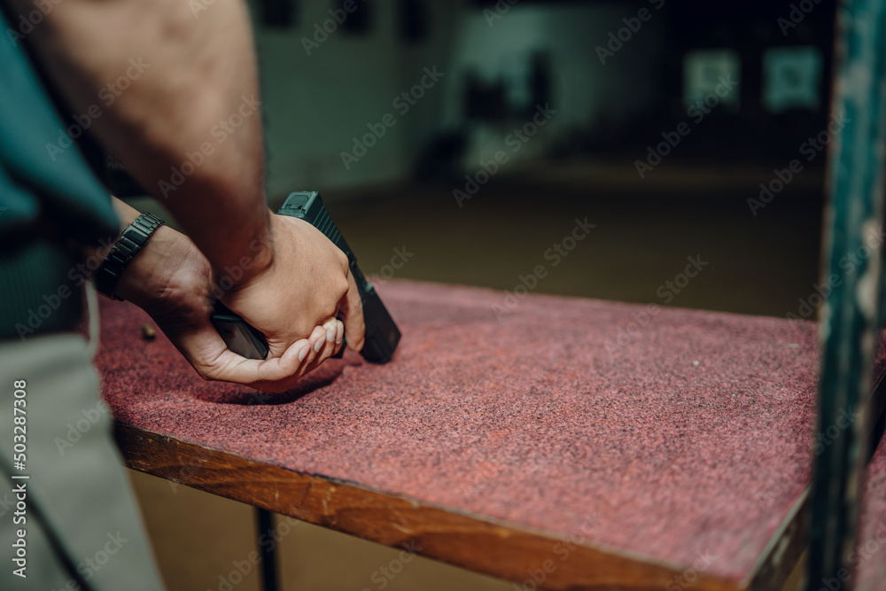 Professionals practice shooting a 9mm pistol inside a shooting range ...