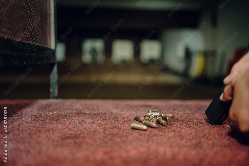 Professionals practice shooting a 9mm pistol inside a shooting range ...