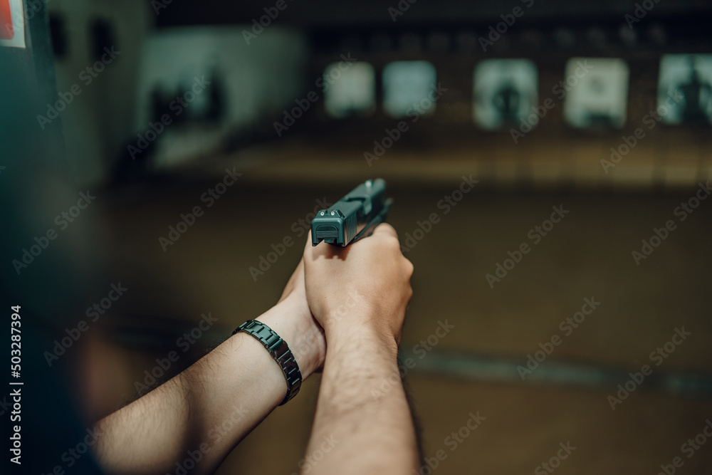 Professionals practice shooting a 9mm pistol inside a shooting range ...