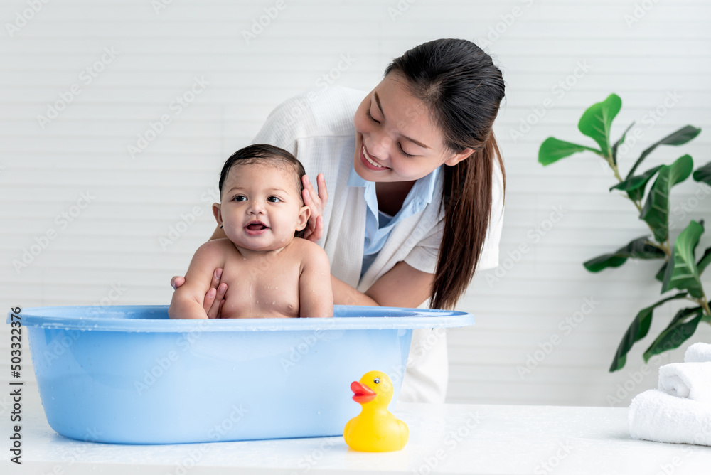 Asian mother Bathing her 7 month old daughter, which the baby smiling ...