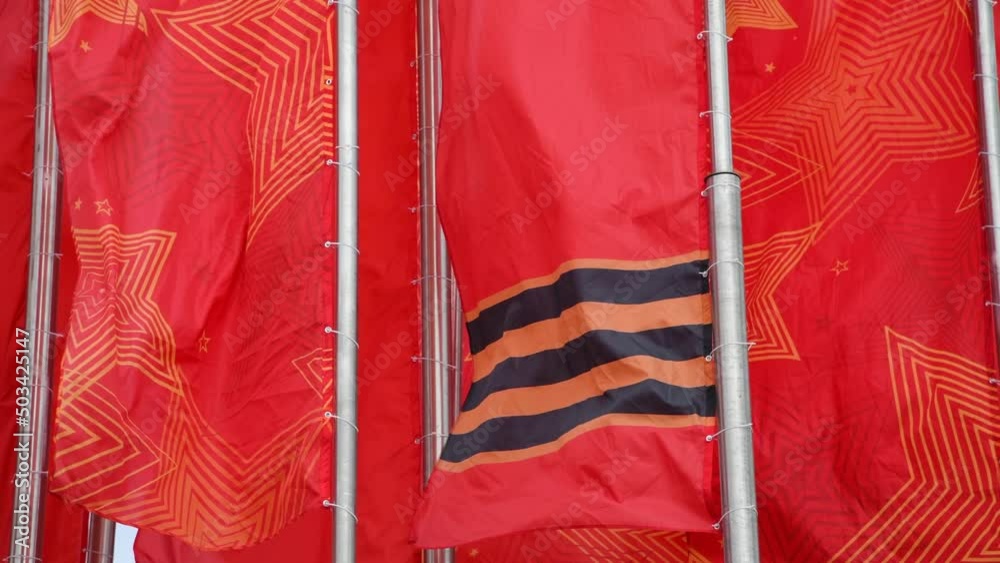 Group of red flags with george ribbons and stars swings on flagpoles ...