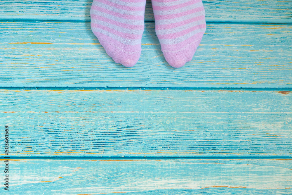 Female feet with lined pink socks isolated on a turquoise blue wooden ...