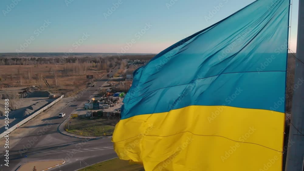 CLOSE UP: Large Ukrainian flag flutters, moving forward, aerial view ...