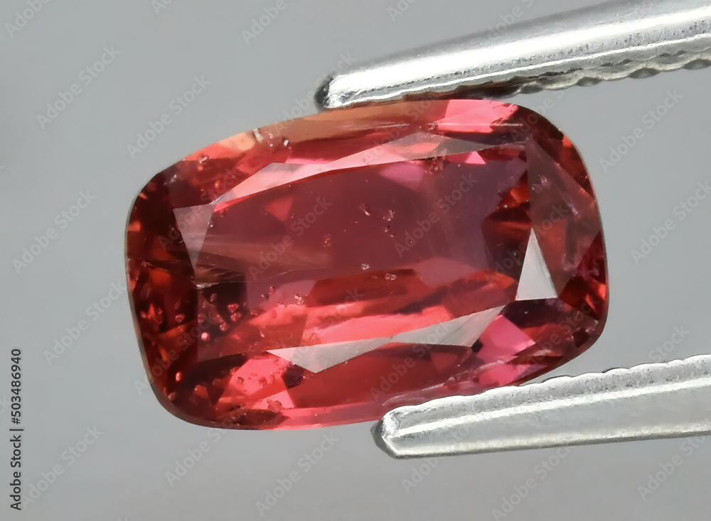 Natural gemstone red sapphire in tweezers on a gray background Stock ...