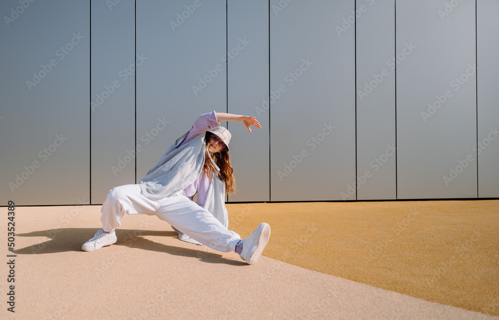 Young hip hop girl in oversize outfit wearing dancing into music ...