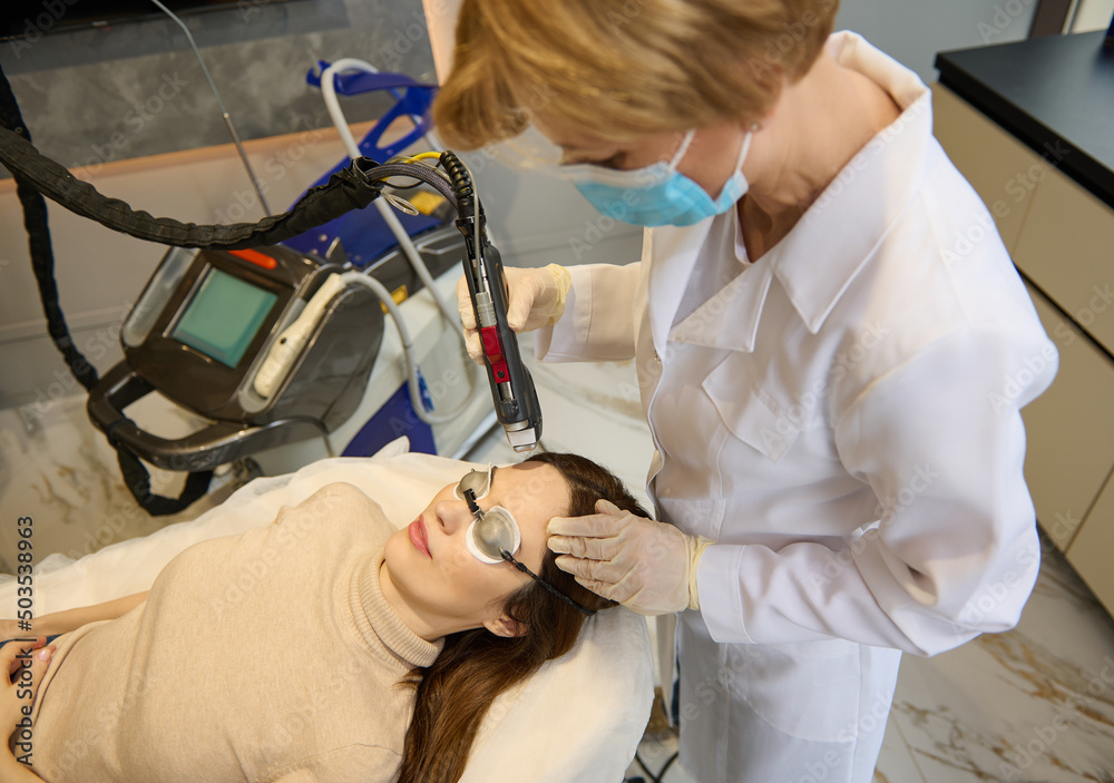 Top view of a young woman receiving facial laser beauty treatment for ...