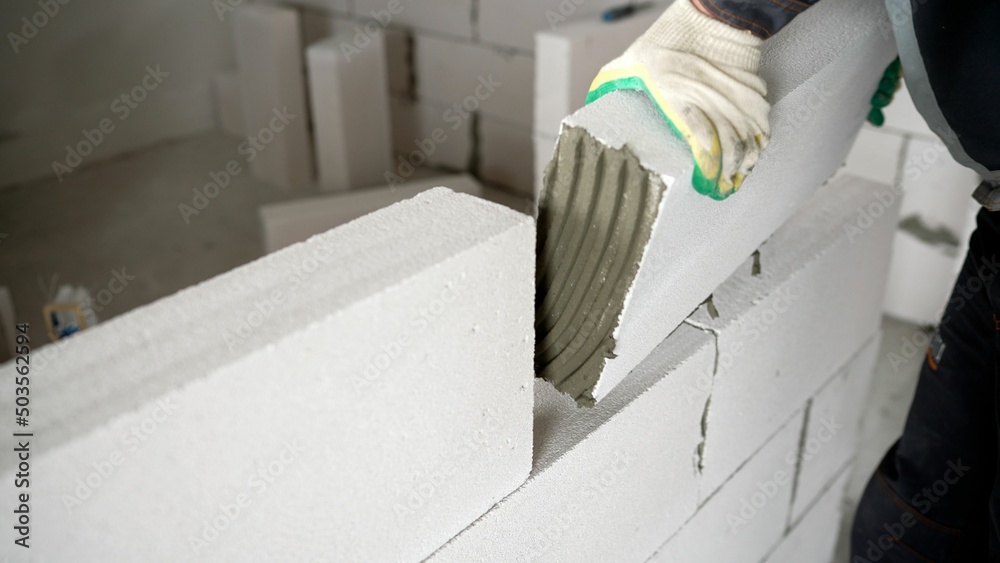 Construction site of a house made of light bricks. The master builds a ...