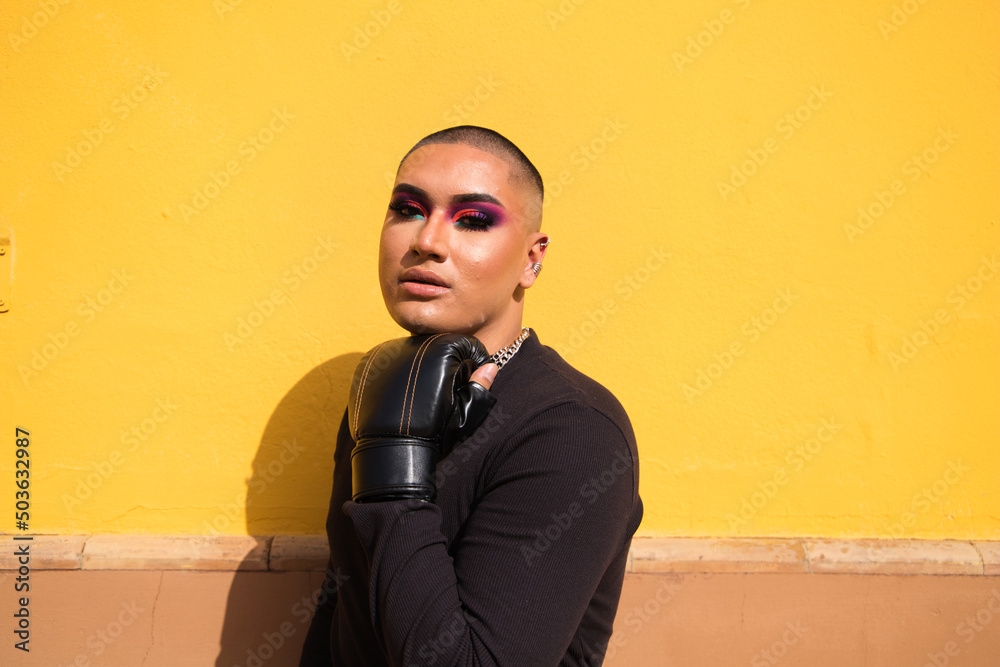 Young non-binary person wears boxing gloves on a mustard yellow ...