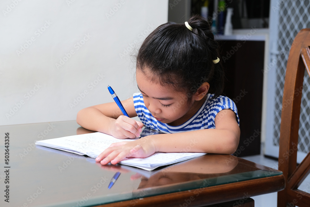 Asian kid study diligently in her home Stock Photo | Adobe Stock