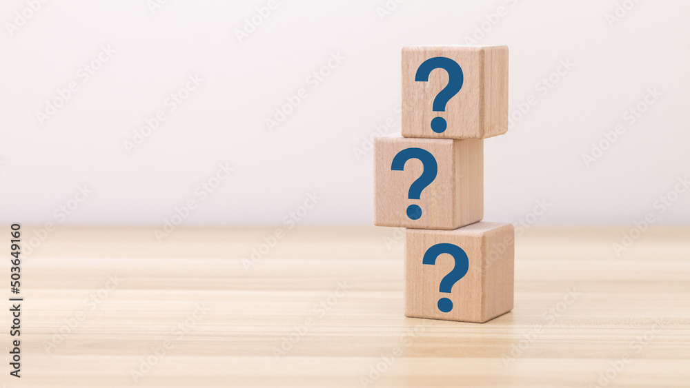Wooden cube block shape with sign question mark symbol on wood table ...