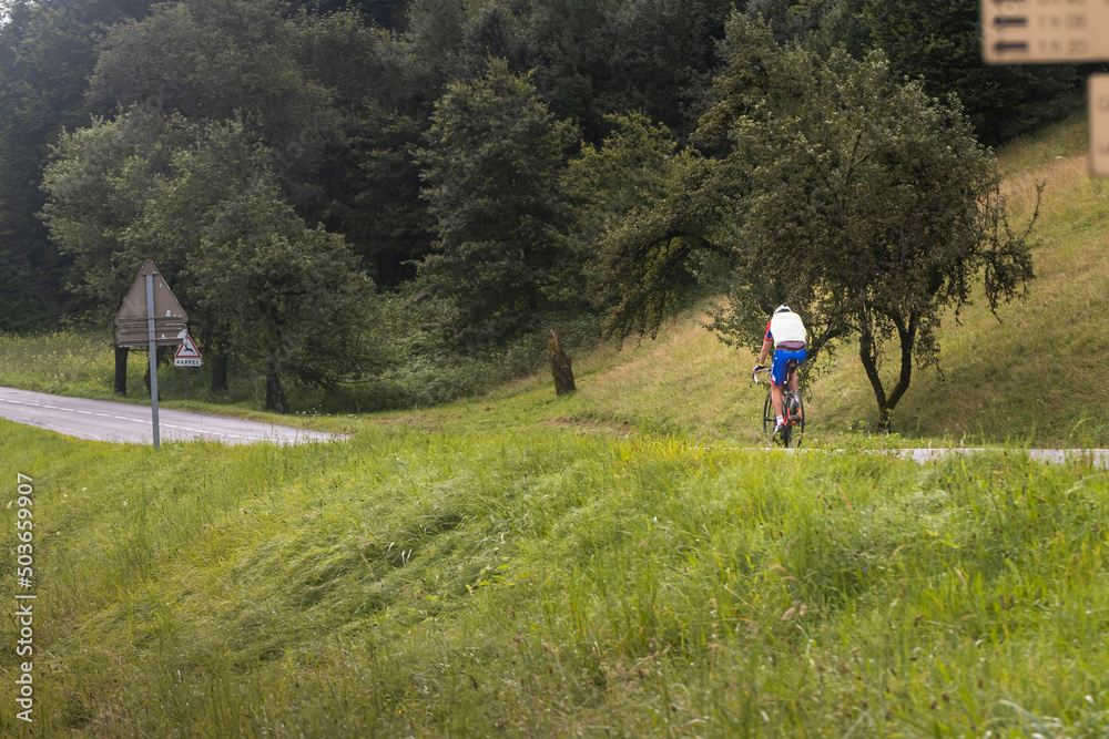 A man rides his bike into the distance. The backshot emphasizes the ...
