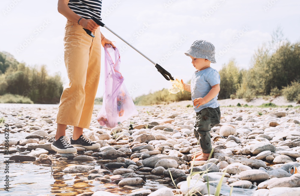 Mother clean up outdoor area from rubbish near her playing toddler son ...
