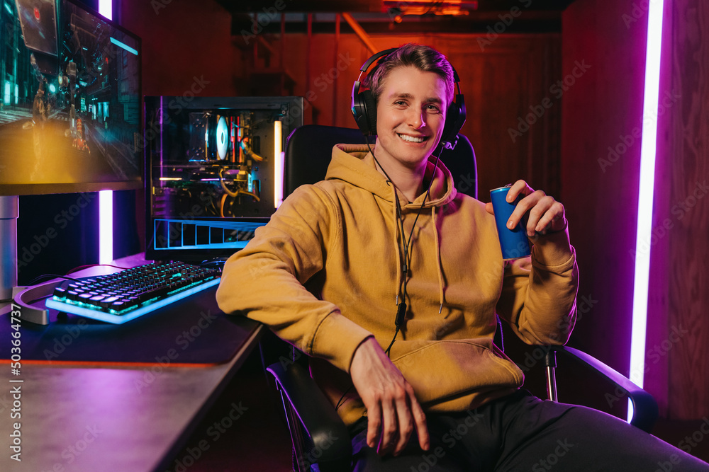 Portrait of smiling pro gamer wearing headset, looking at camera ...