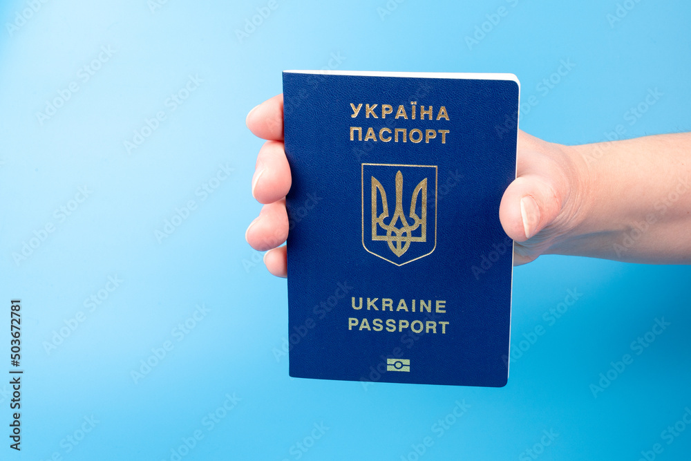 Passport of a citizen of Ukraine in a female hand on a blue background ...