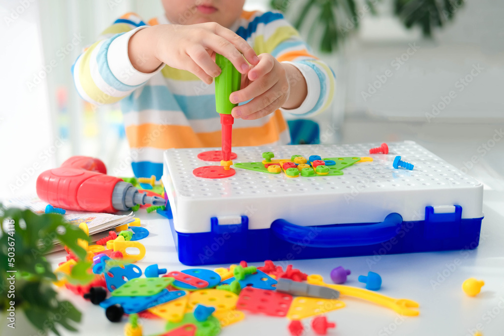 Little boy playing set with a screwdriver and a drill, and screws and ...