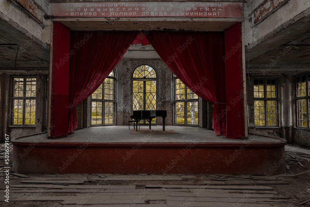 Old grand piano on stage with velvet curtains in abandoned concert hall ...