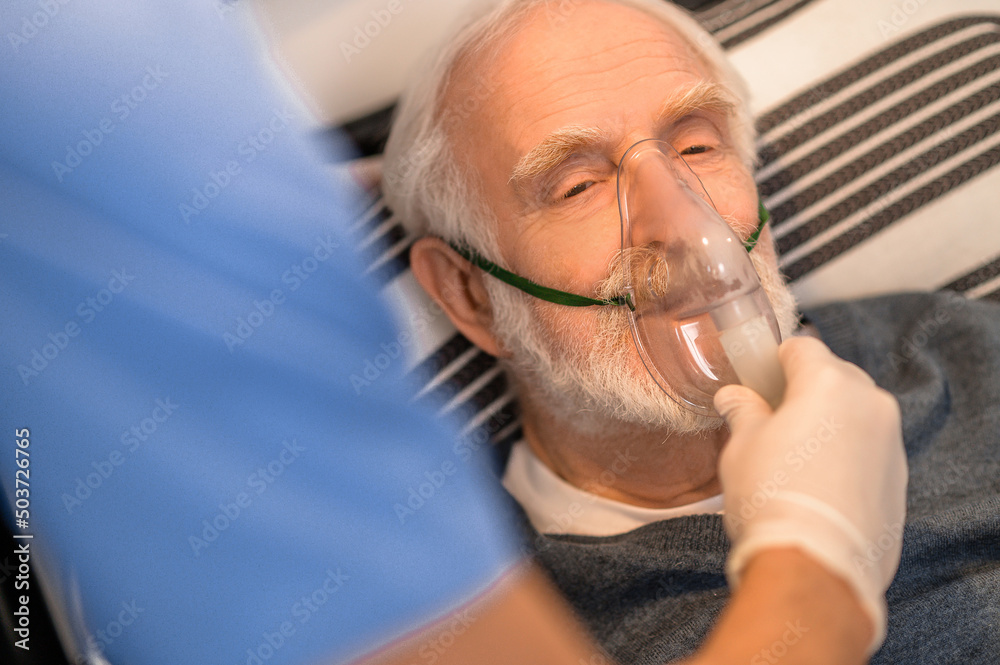 Experienced nurse conducting an oxygenation procedure on a bedridden ...