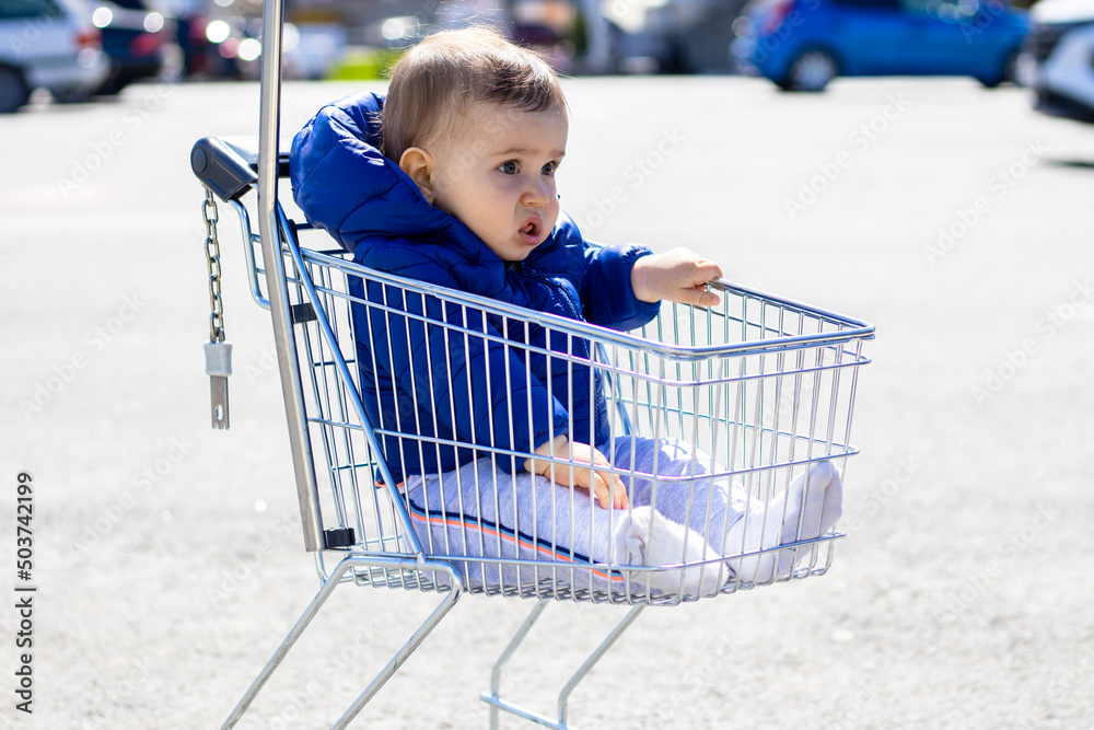 cute baby boy sitting in little shopping cart for kids. happy adorable ...