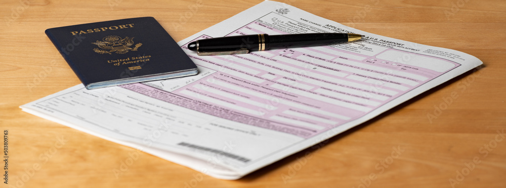 Application for a U.S. Passport on a wooden table with a passport book ...