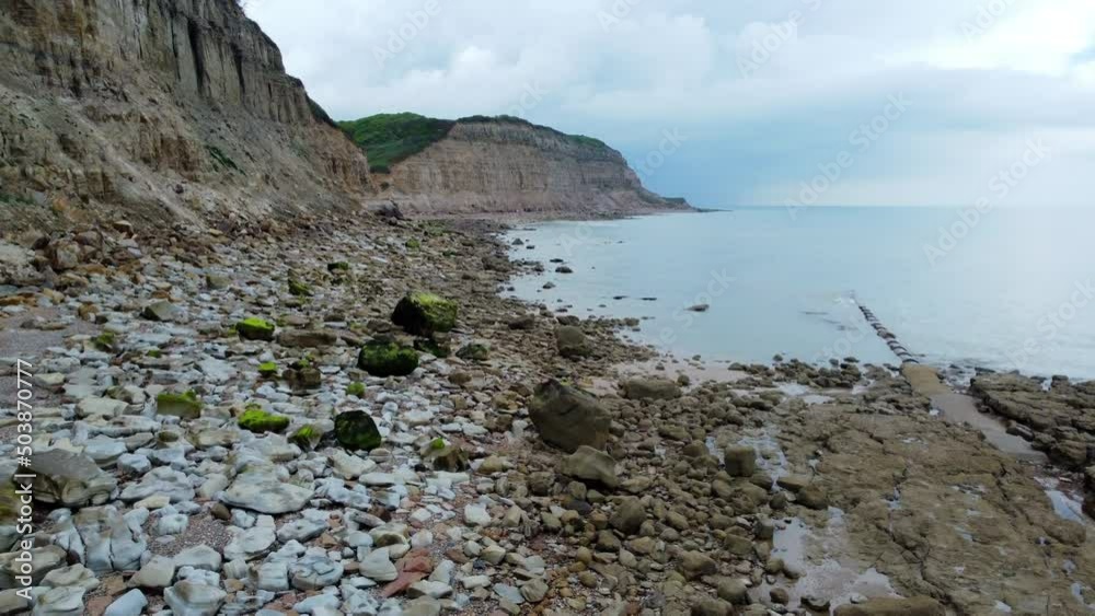 An aerial view rises up from a rocky beach revealing a coastline of ...