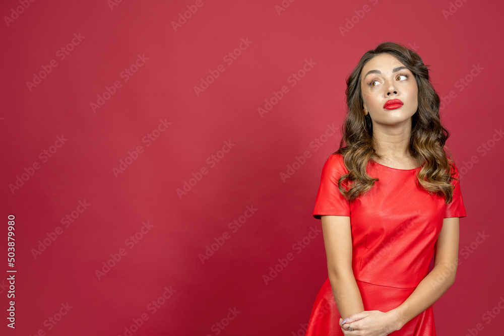 Beautiful brunette woman saddened in a red dress on a red background ...