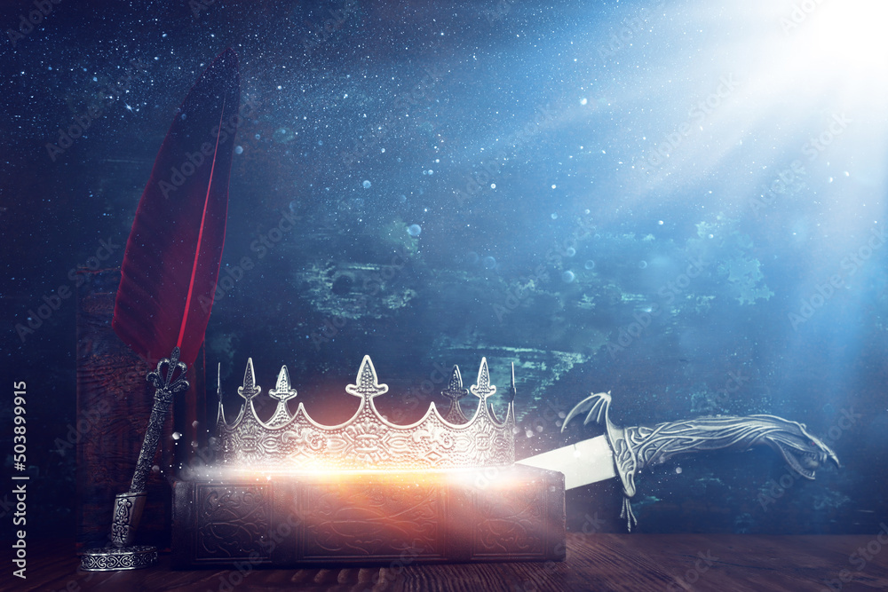 low key image of beautiful queen or king crown over antique book next ...