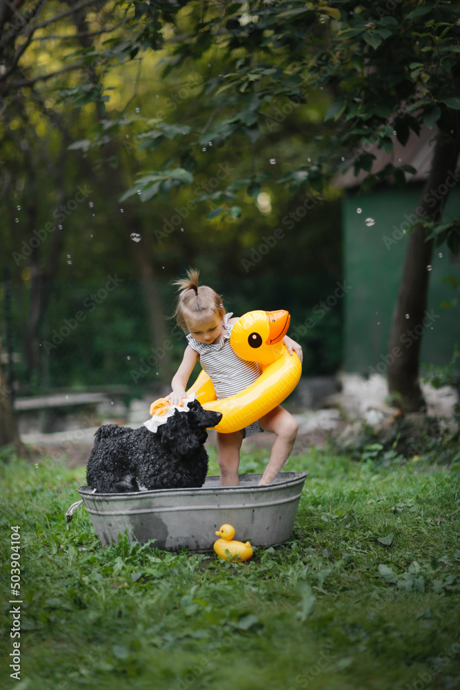 cute child with yellow inflatable duck bathes in iron tub with black ...