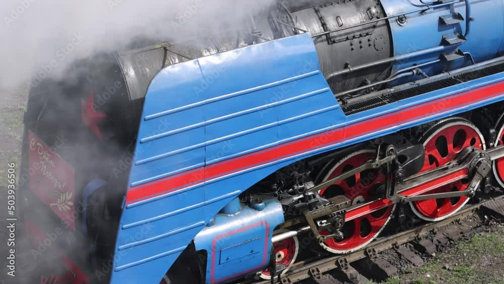 A World War II steam locomotive moves slowly and blows steam. Vintage ...