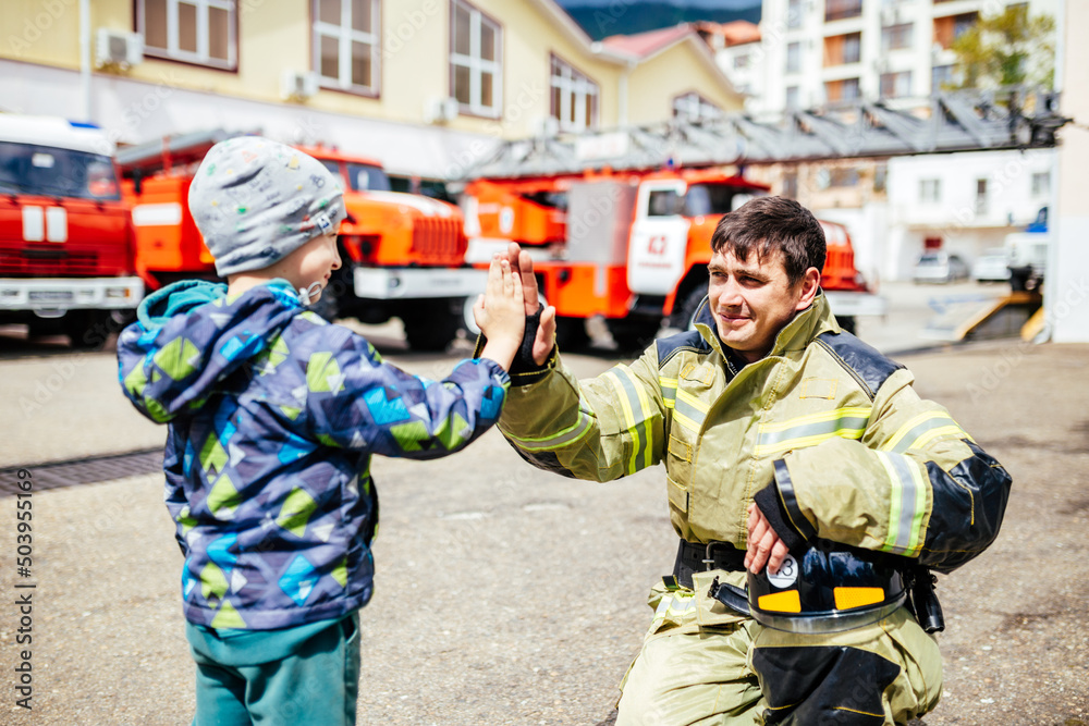 Portrait of a firefighter with kid standing against the backdrop of ...
