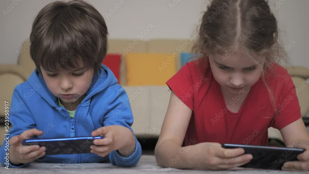 Children Playing Games In Phone at Home Lying on Floor. Kids Playing ...