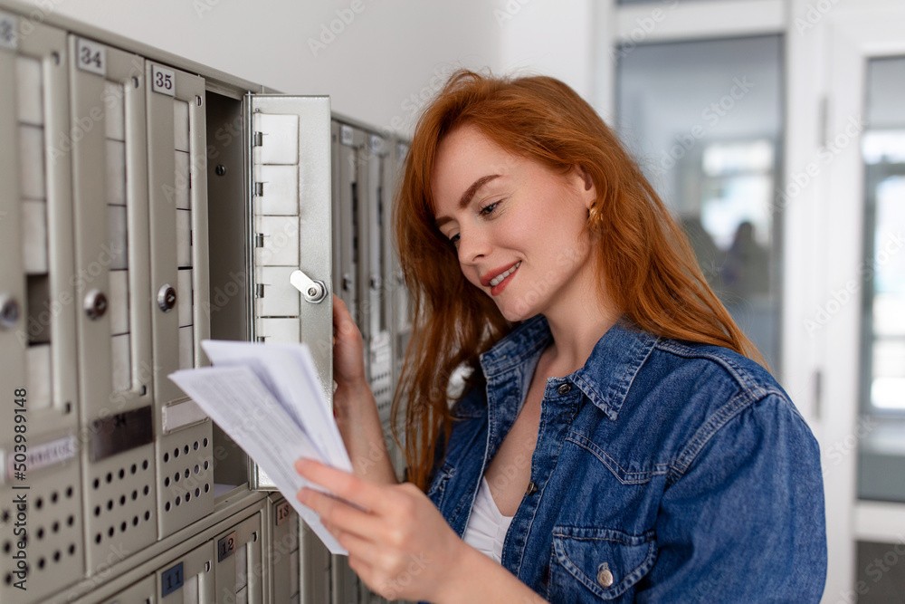 Positive casually dressed woman holding new letter from postal delivery ...