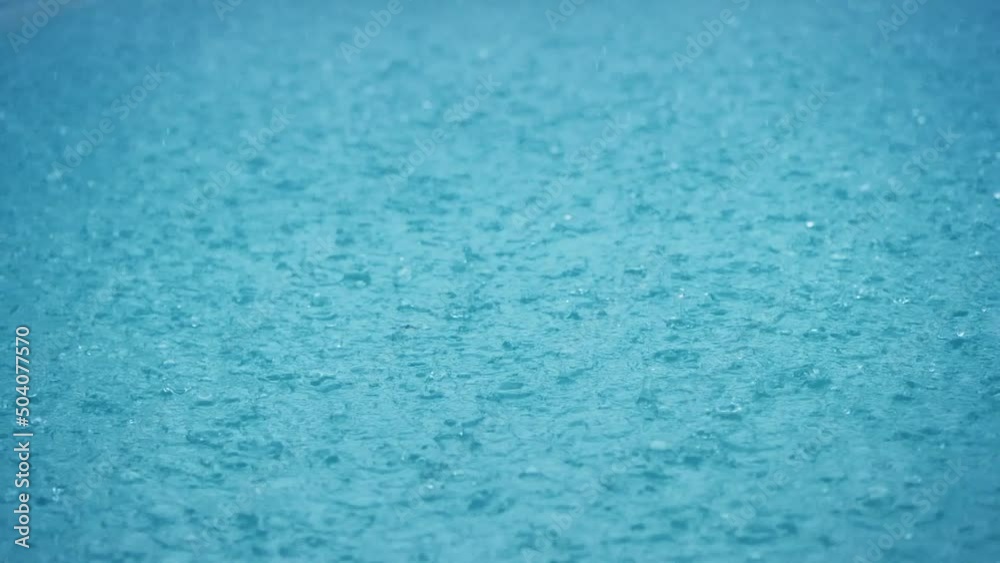 Rain Water Droplets Splash into a Blue Puddle. Slow motion close up of ...