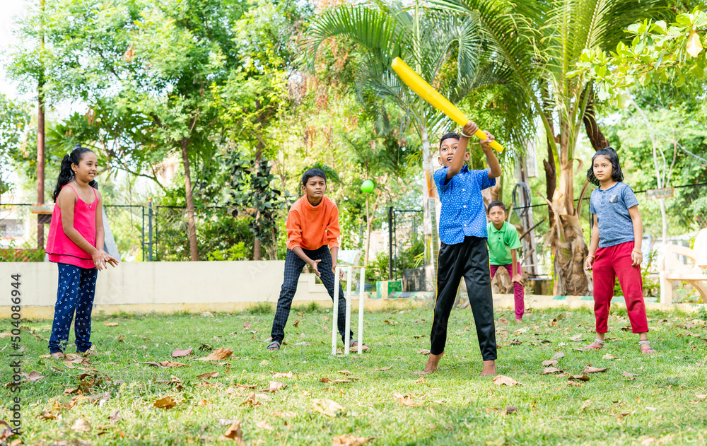 young kid running by hitting the ball while playing cricket at park for ...