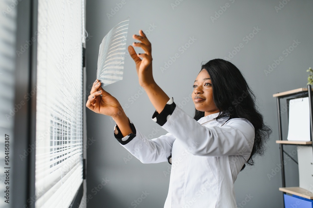 Young attractive african female doctor radiologist looking at x-ray ...