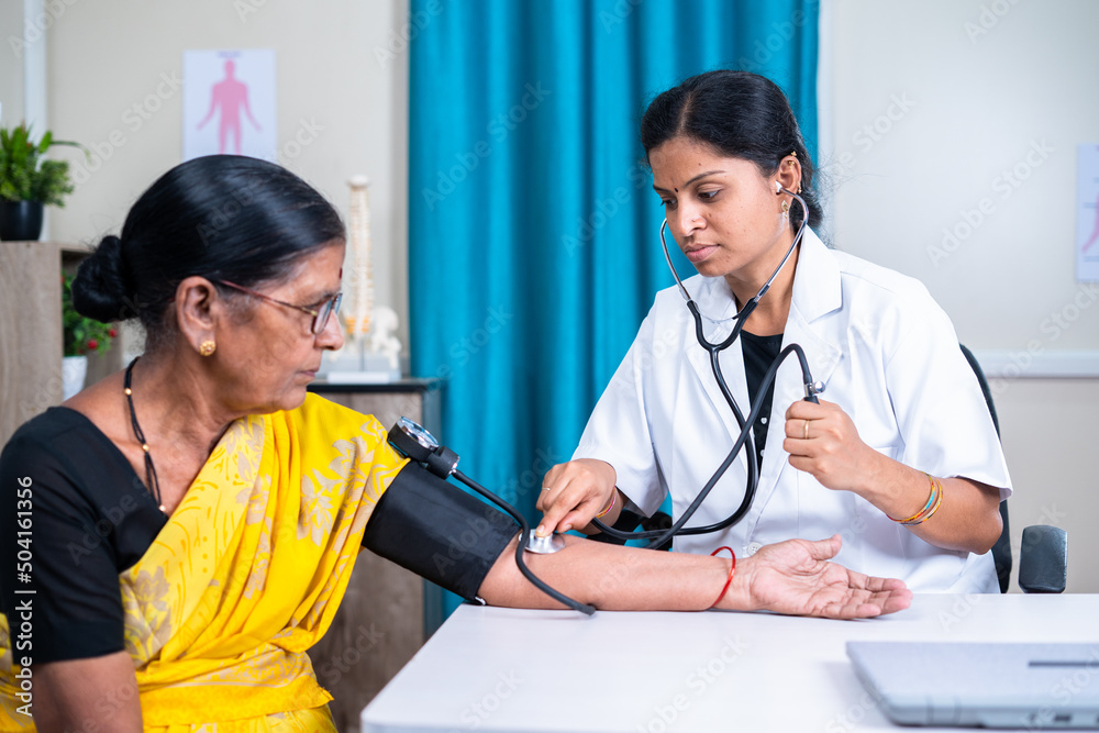 Doctor checking blood pressure or bp of senior woman patient at ...