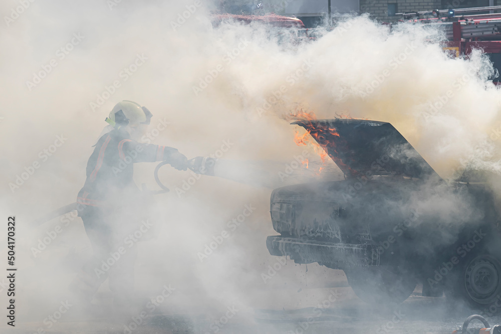 A firefighter extinguishes a car with a fire extinguisher. Fire ...