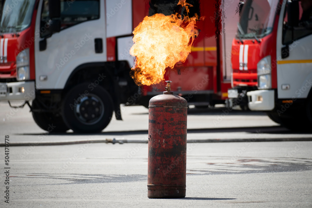 an ignited gas cylinder on background of a fire truck on the street ...