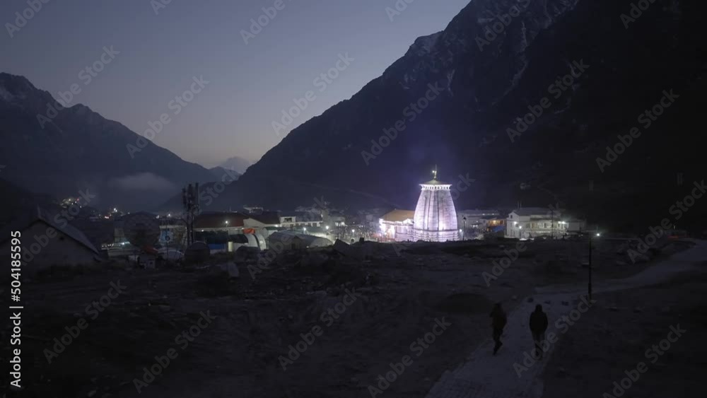 Night scene with illuminated temple, silhouette of people walking ...