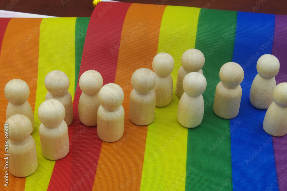 LGBT pride parade concept. Many wooden figures in a row on rainbow LGBT ...