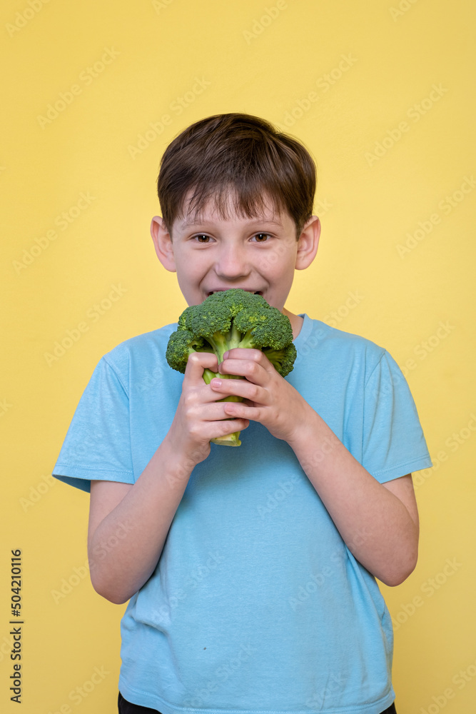 The boy is holding broccoli. Portrait of a funny boy in a blue t-shirt ...
