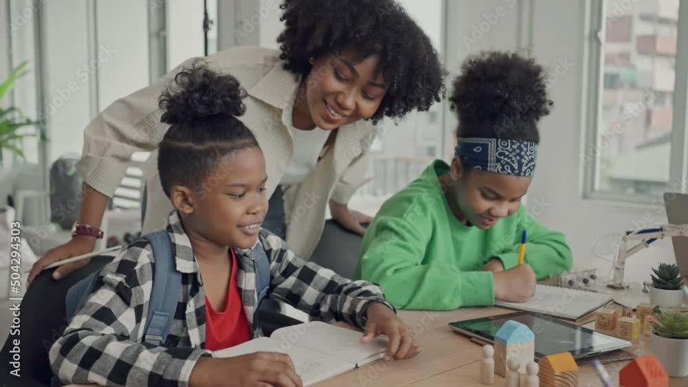 African American female teacher standing with pupils teaching writing ...