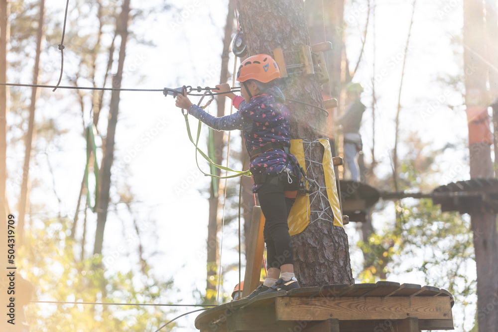 Child in forest adventure park. Kids climb on high rope trail. Agility ...