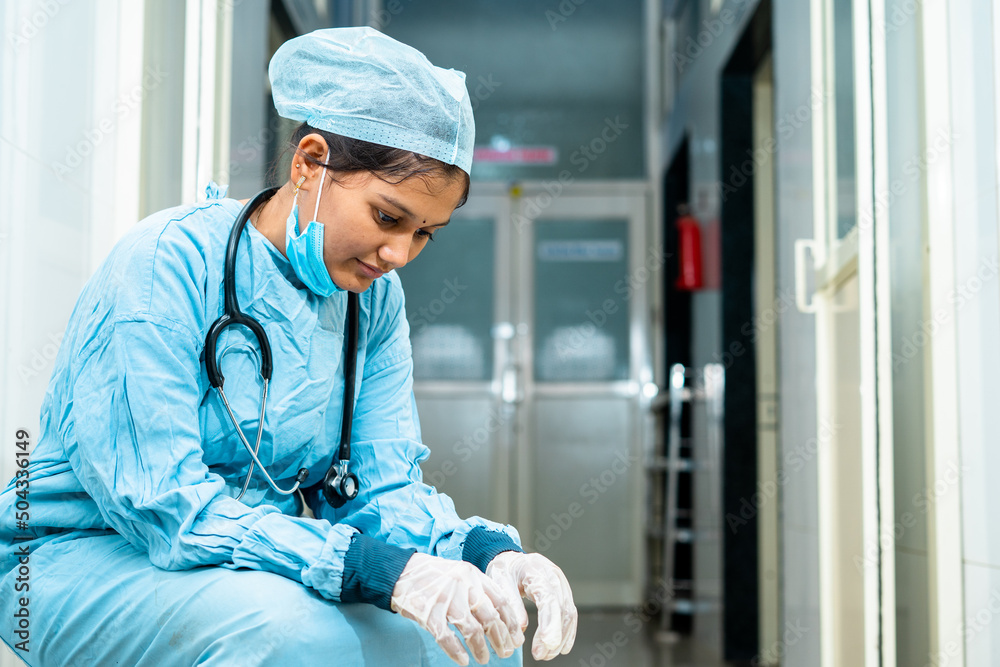 thoughtful medical practitioner in operation gown sitting outside the ...
