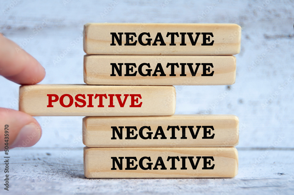 Negative and positive text on wooden blocks with hand placing a wooden ...