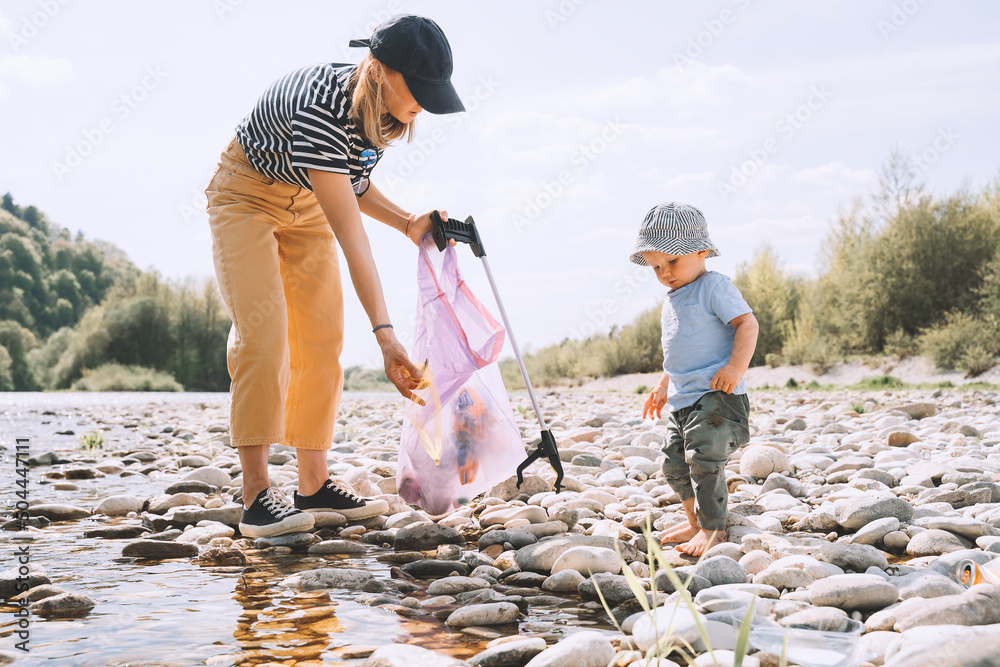 Foto Stock Mother clean up outdoor area from rubbish near her playing ...