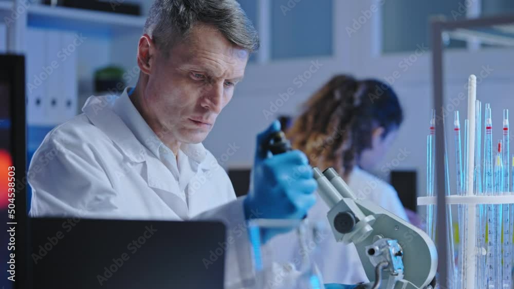 Medical laboratory scientist examining infected cell under microscope ...