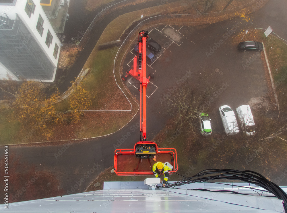 5G network installation, technicians work on a building using the lift ...