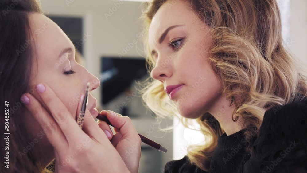 Young woman making makeup in dressing makeup room. Lips make up process ...