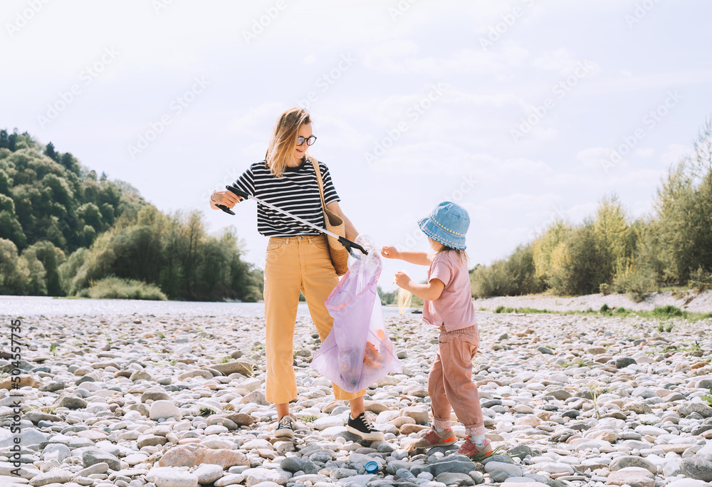 Woman and little girl helping clean up outdoor area from rubbish ...