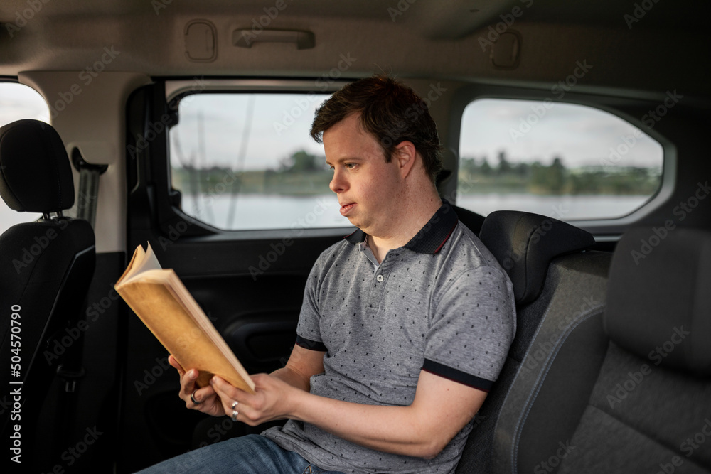 Man with down syndrome reading a book Stock Photo | Adobe Stock